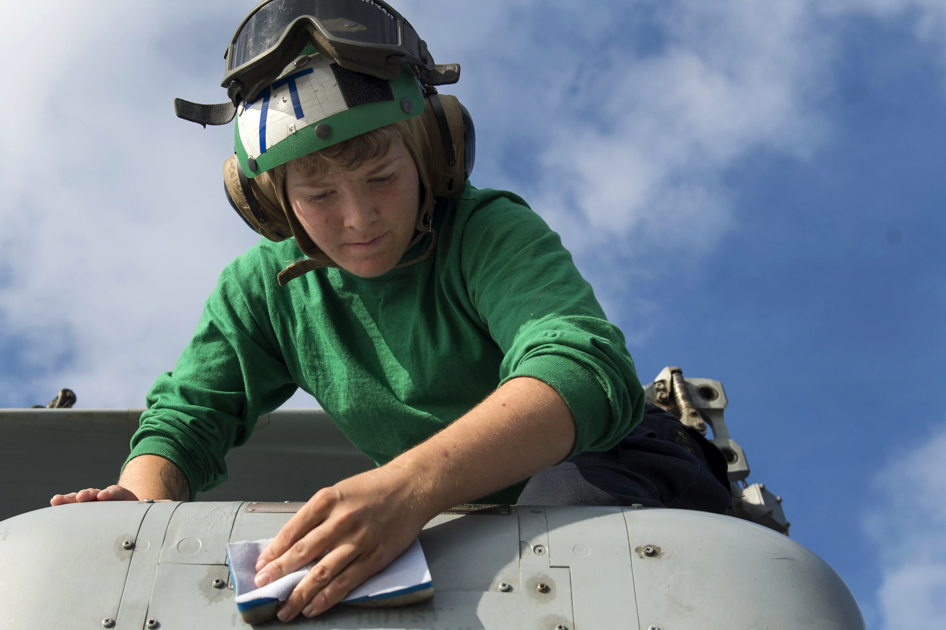 U.S. Navy Seaman Jamie Badgett helps clean an MH-60R Seahawk helicopter ...