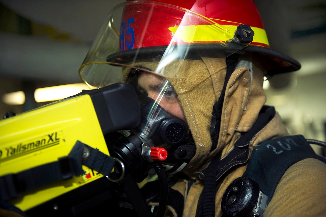 A U.S. sailor uses a Naval Firefighting Thermal Imager to fight a ...