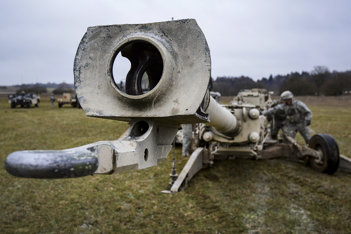 U.S. soldiers move an M777 howitzer into firing position for a live ...