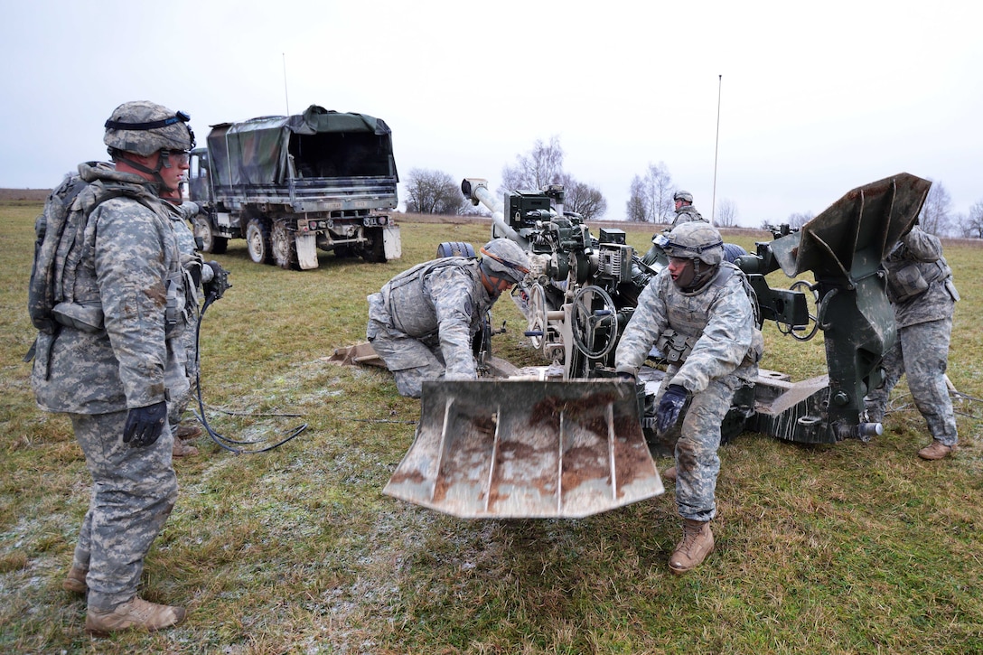 U.S. soldiers move an M777 howitzer into firing position for a live ...