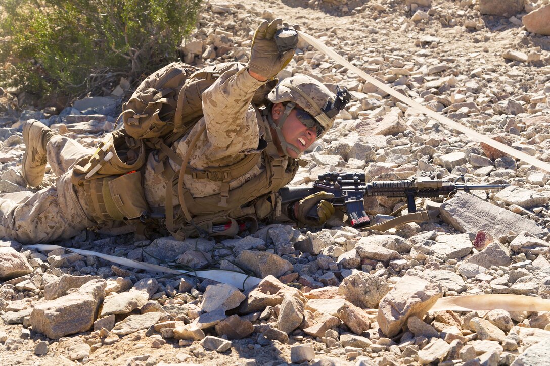 A Marine marks a lane through a simulated mine field using tape while ...