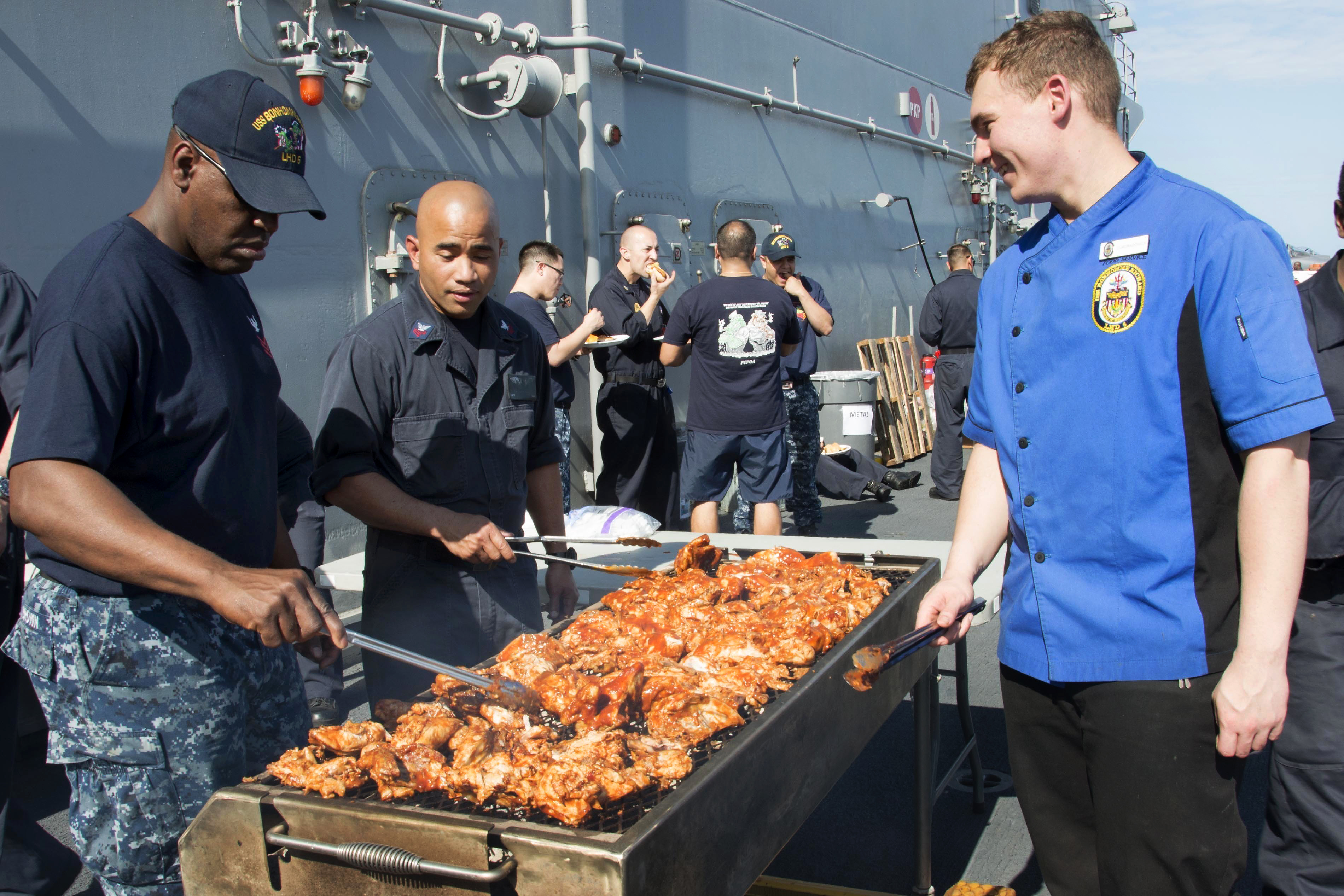 U.S. sailors prepare barbecue chicken for a Fourth of July picnic on ...