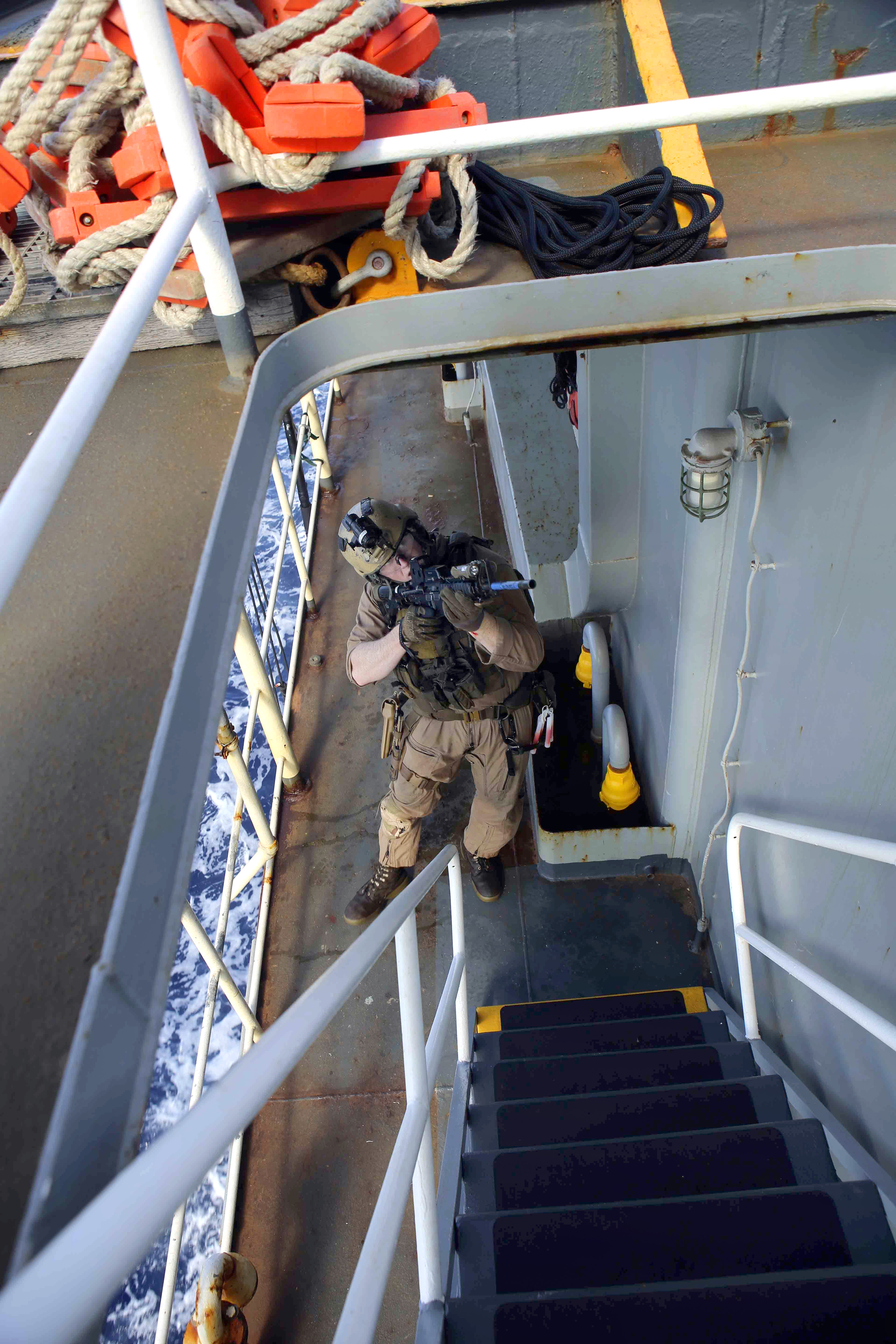 A U.S. Marine clears a ladder well aboard a vessel while conducting a ...