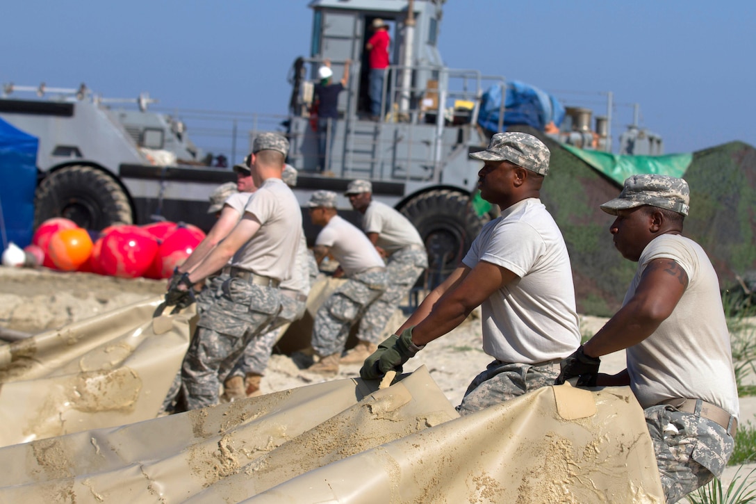 U.S. soldiers prepare a 50,000 gallon collapsible bag of water to ...