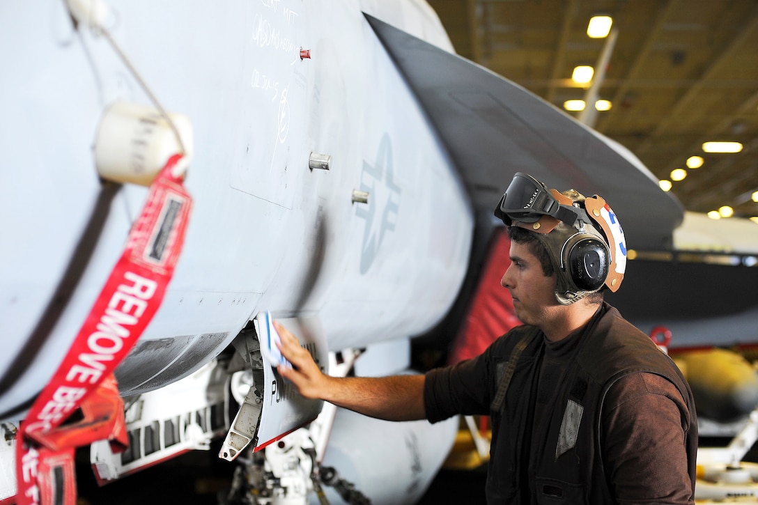 U.S. Navy Seaman Nicholas Bunner cleans the exterior of an F/A-18E ...