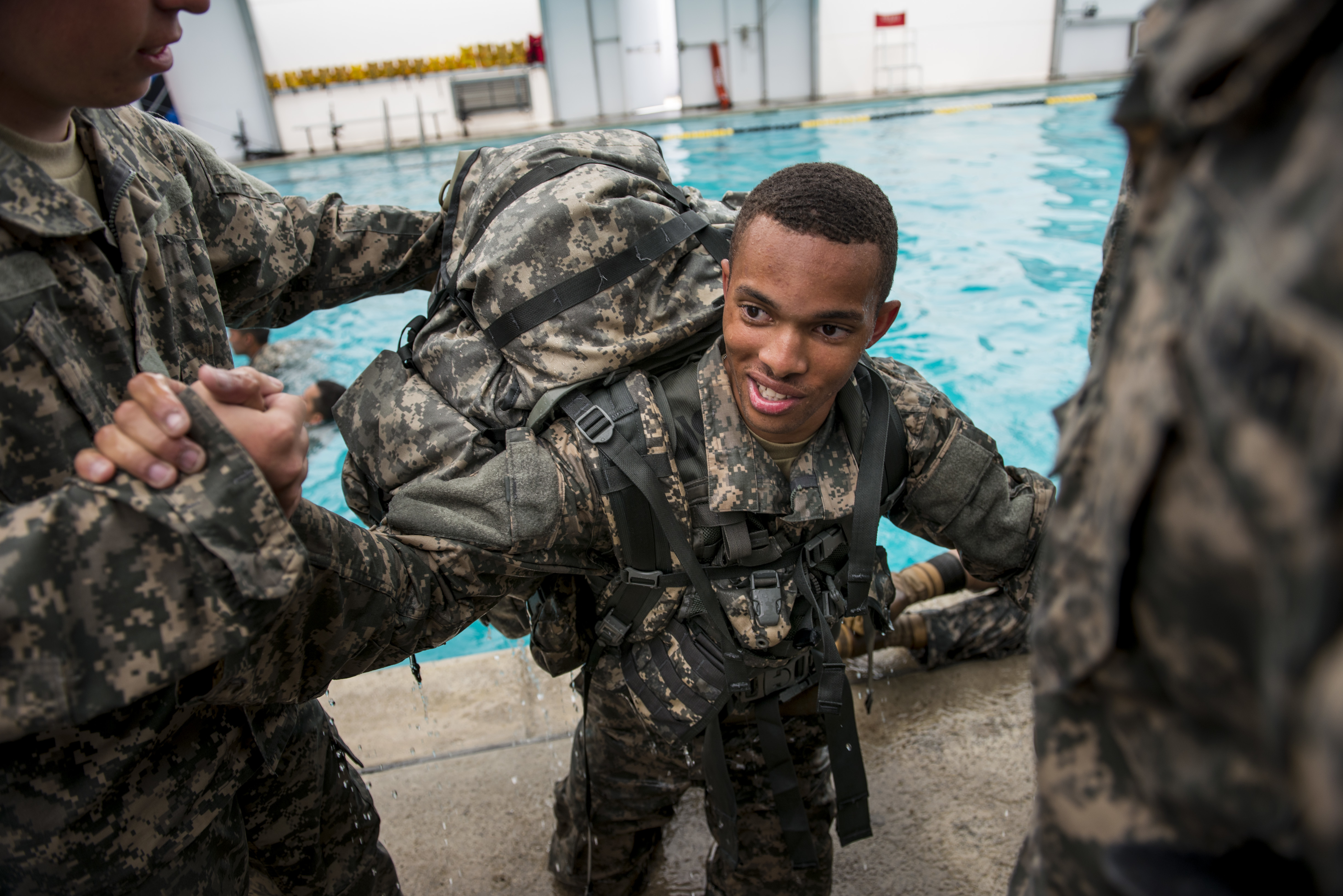 Soldiers help a team member out of the water after swimming 25 meters ...