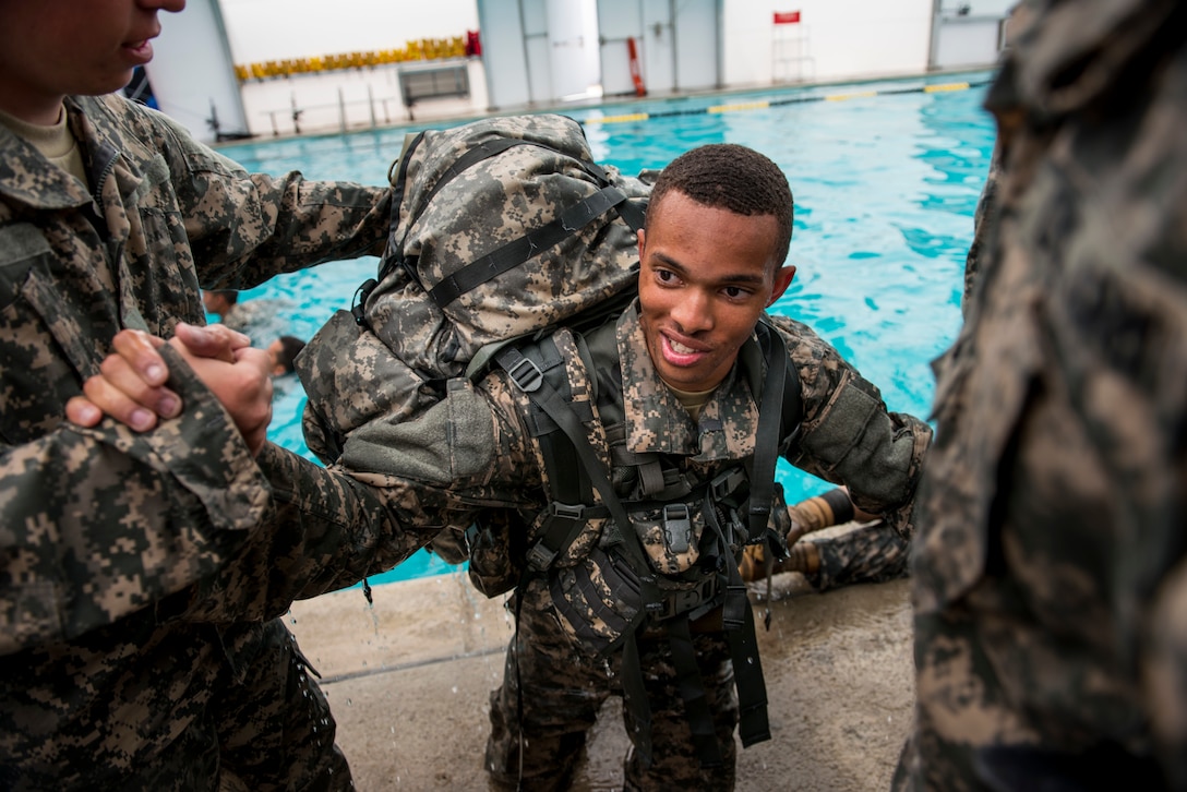 Soldiers help a team member out of the water after swimming 25 meters ...