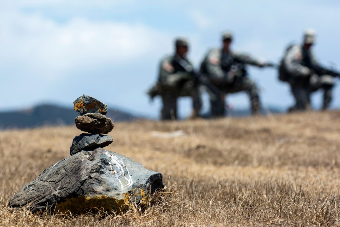 Army Reservists react to a rock formation indicating an improvised ...