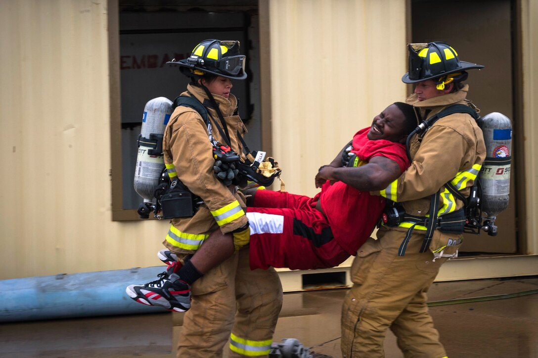 Sailors, civilian firefighters and first responders carry a simulated ...