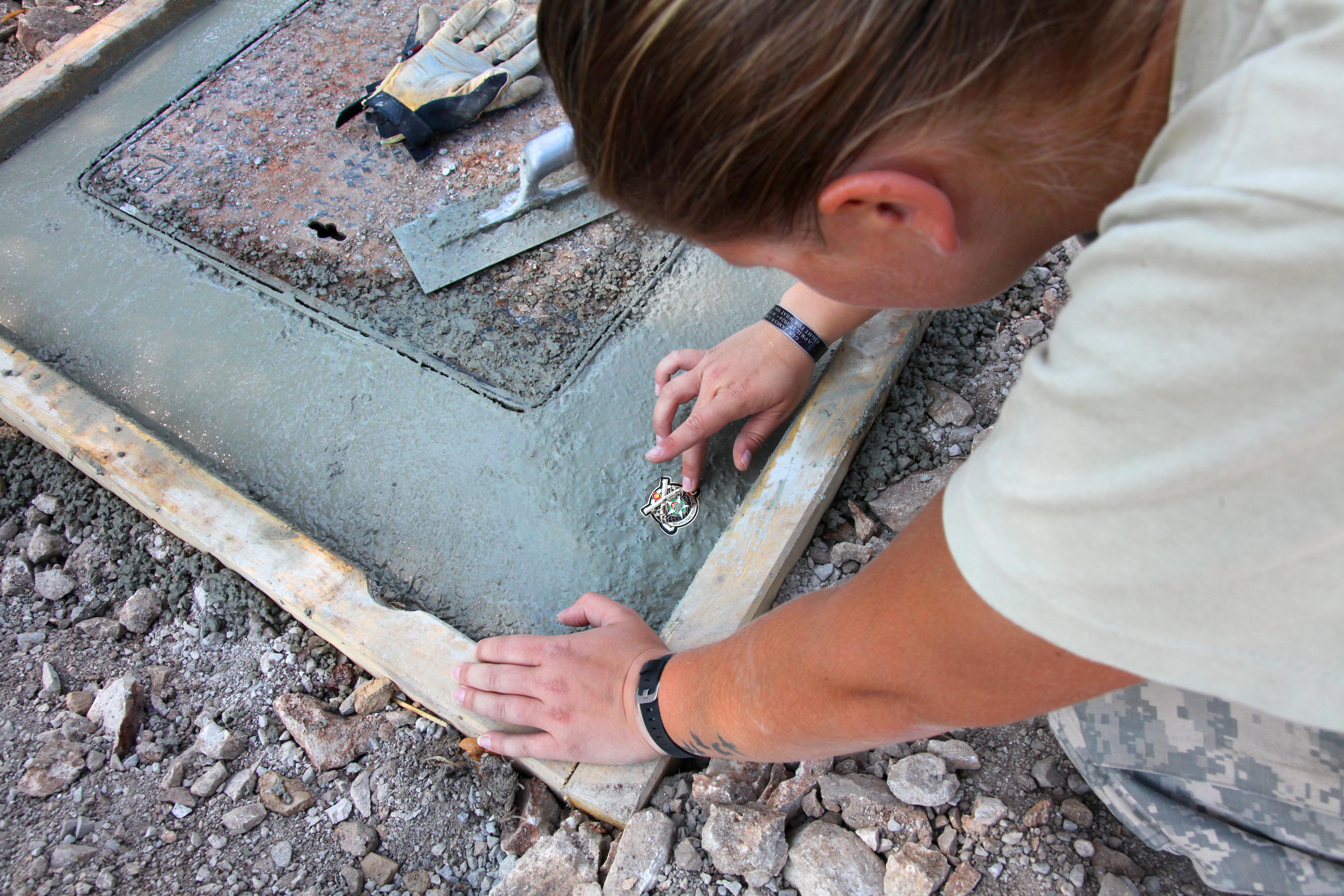 U.S. Army Sgt. Rachel Cornett finishes the concrete around an in-ground ...
