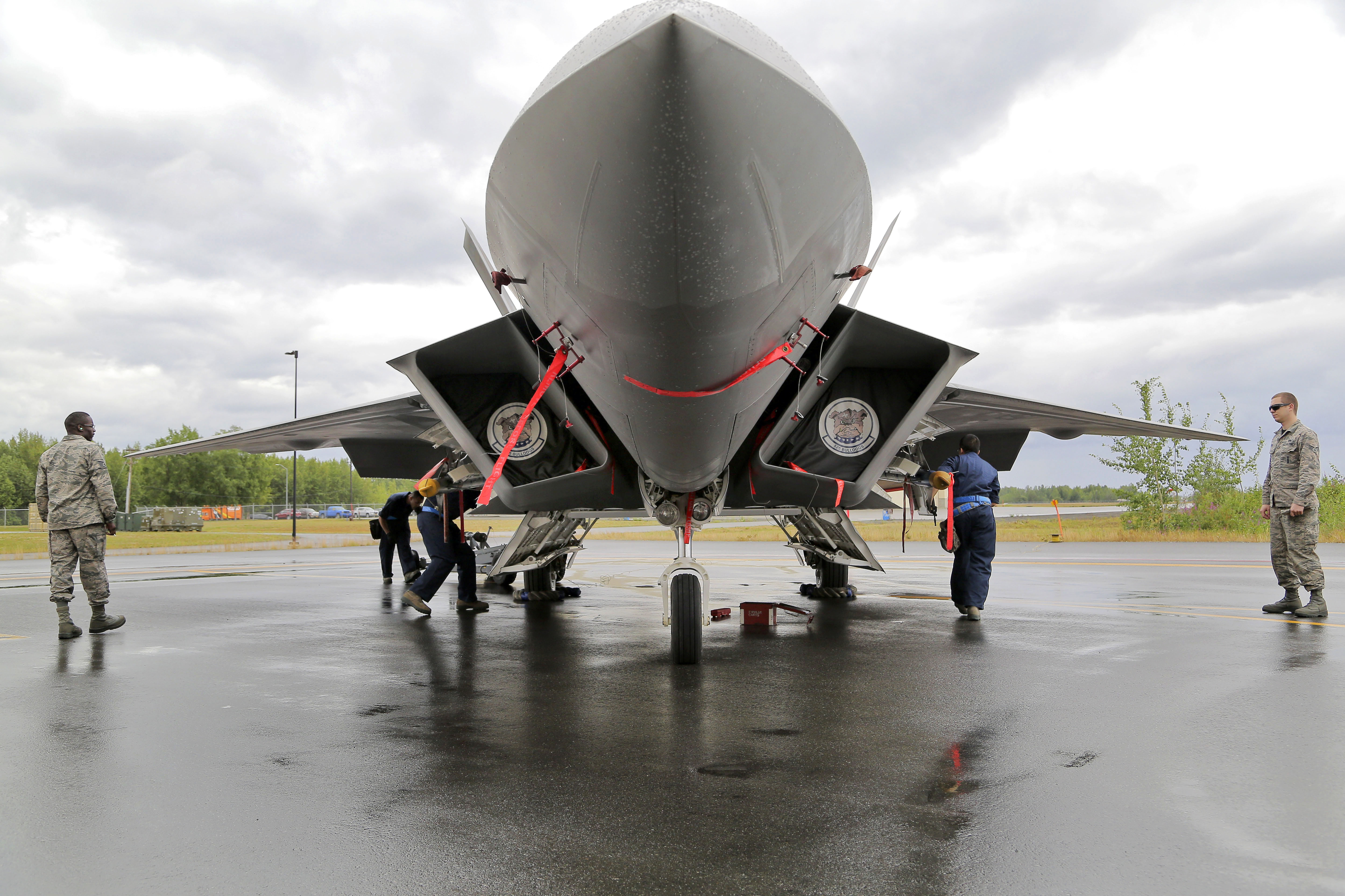 Air Force evaluators supervise weapon loaders as they arm an F-22 ...