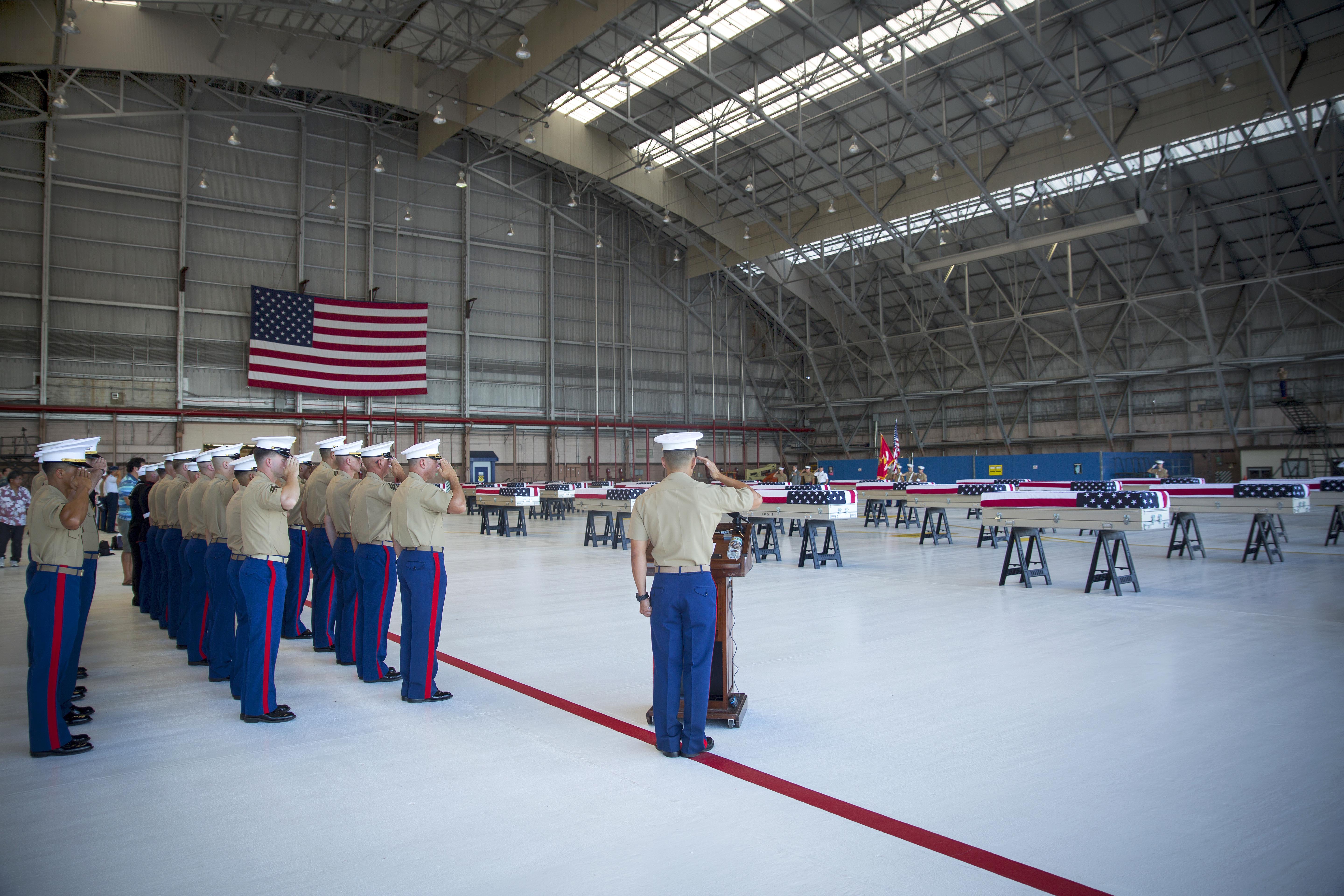 Marines salute as "Taps" is played at the end of a Dignified Transfer ...