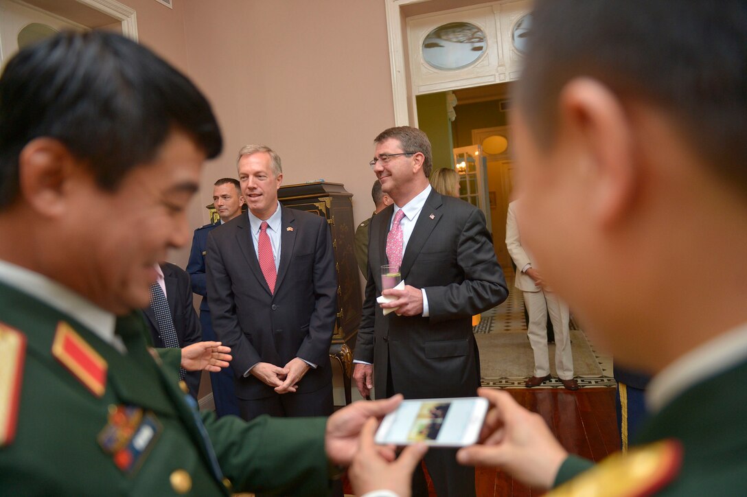 Vietnamese military officers, foreground, look over a smart phone photo ...