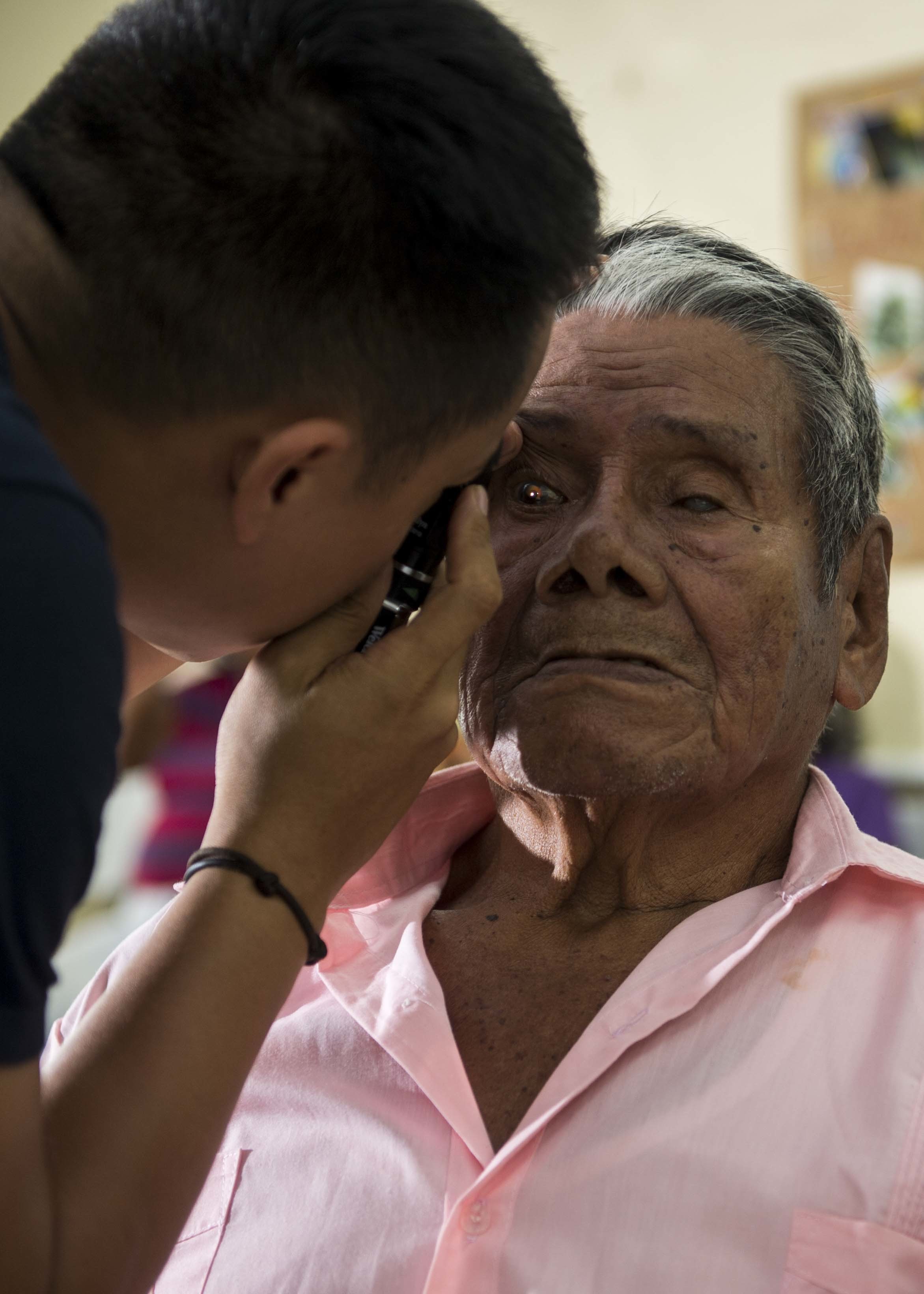U.S. Navy Lt. Kevin Hoang examines a patient at a medical site ...