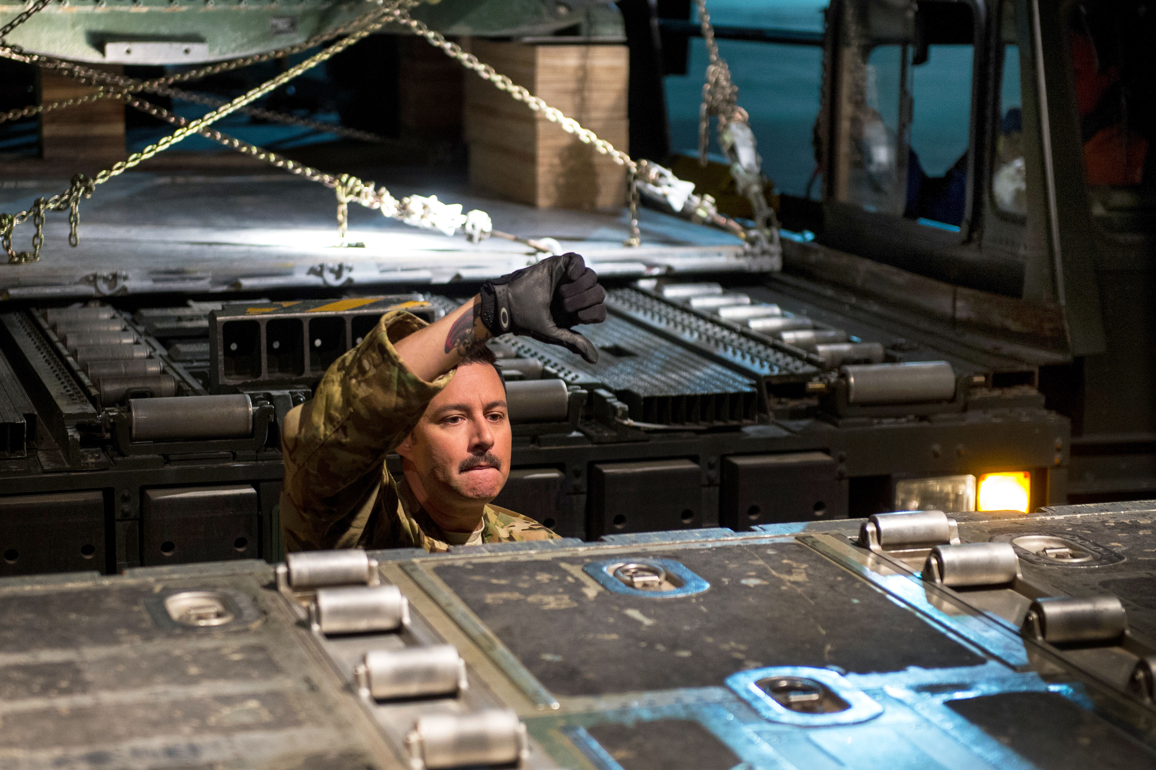 U.S. Air Force Master Sgt. Jose Davila guides a palletized howitzer ...
