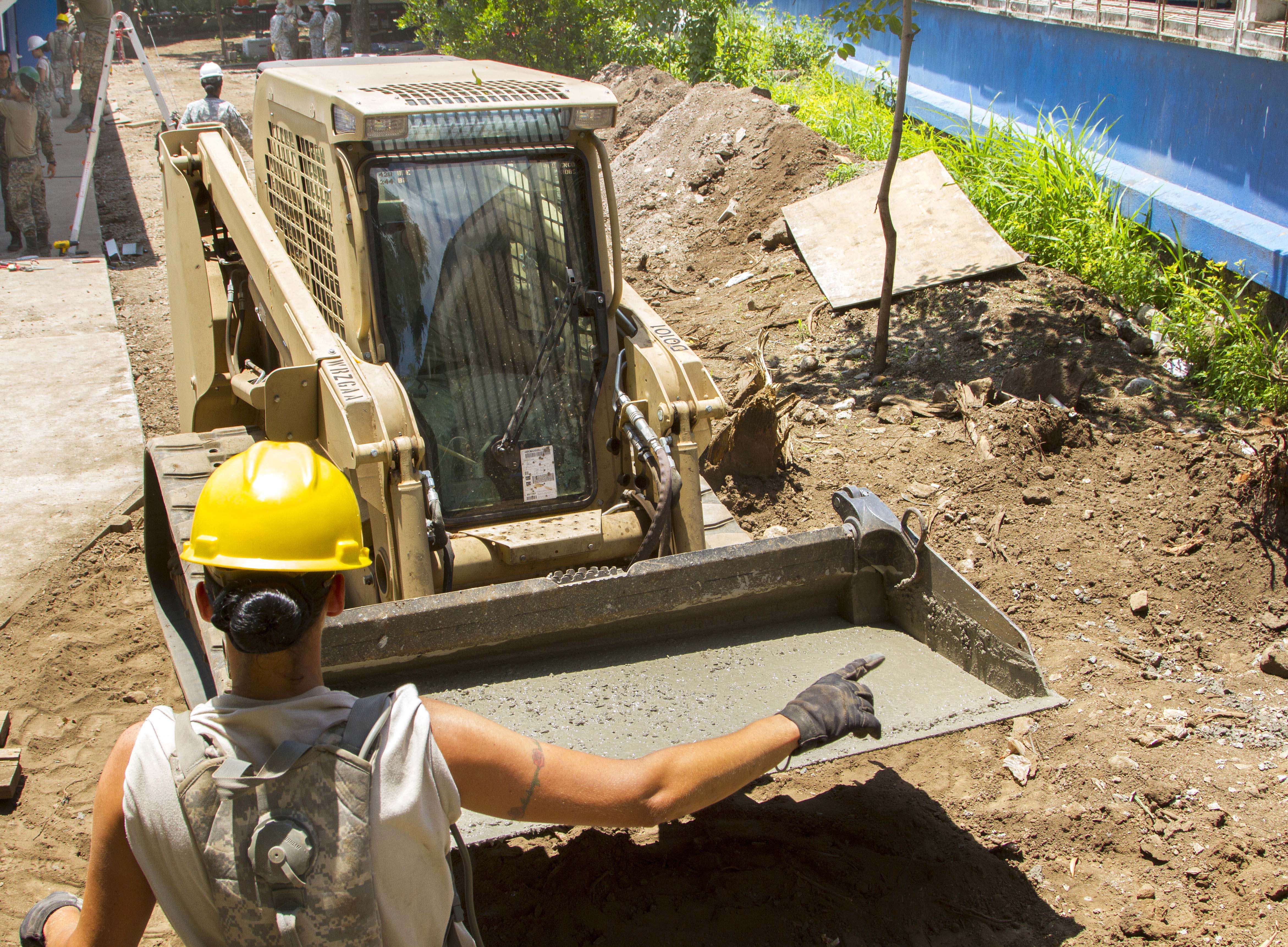 U.S. Army Staff Sgt. Patricia Hightower directs a skid-steer loader to ...