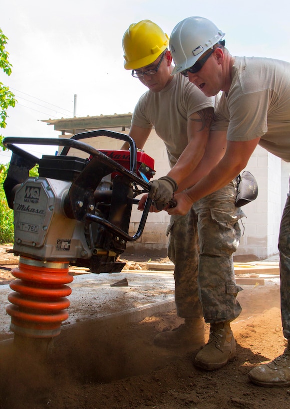 U.S. Army Sgt. Chad Thompson and Pfc. Anthony Hernandez use a vibratory ...