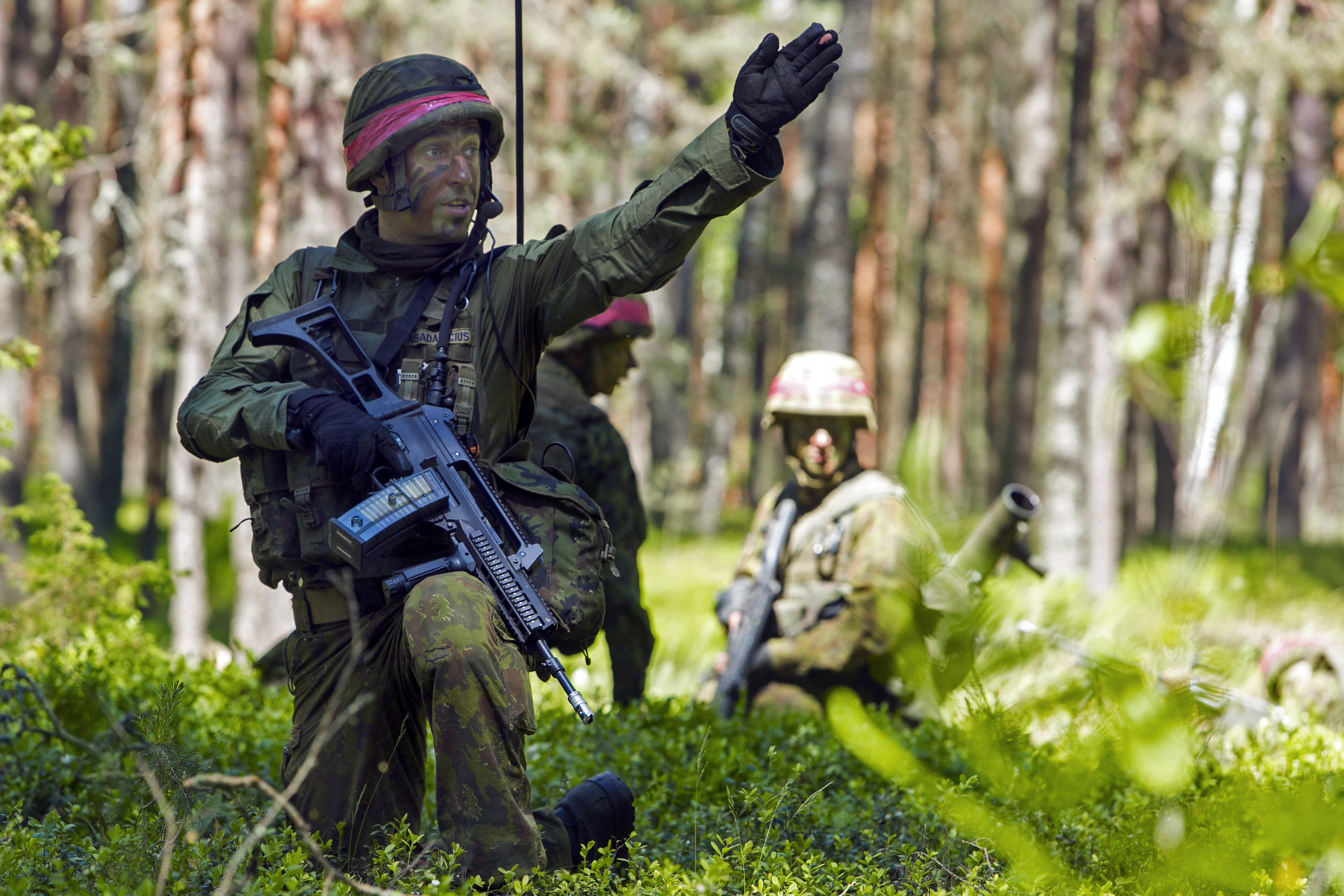 A Lithuanian soldier points in the direction for his team to advance ...