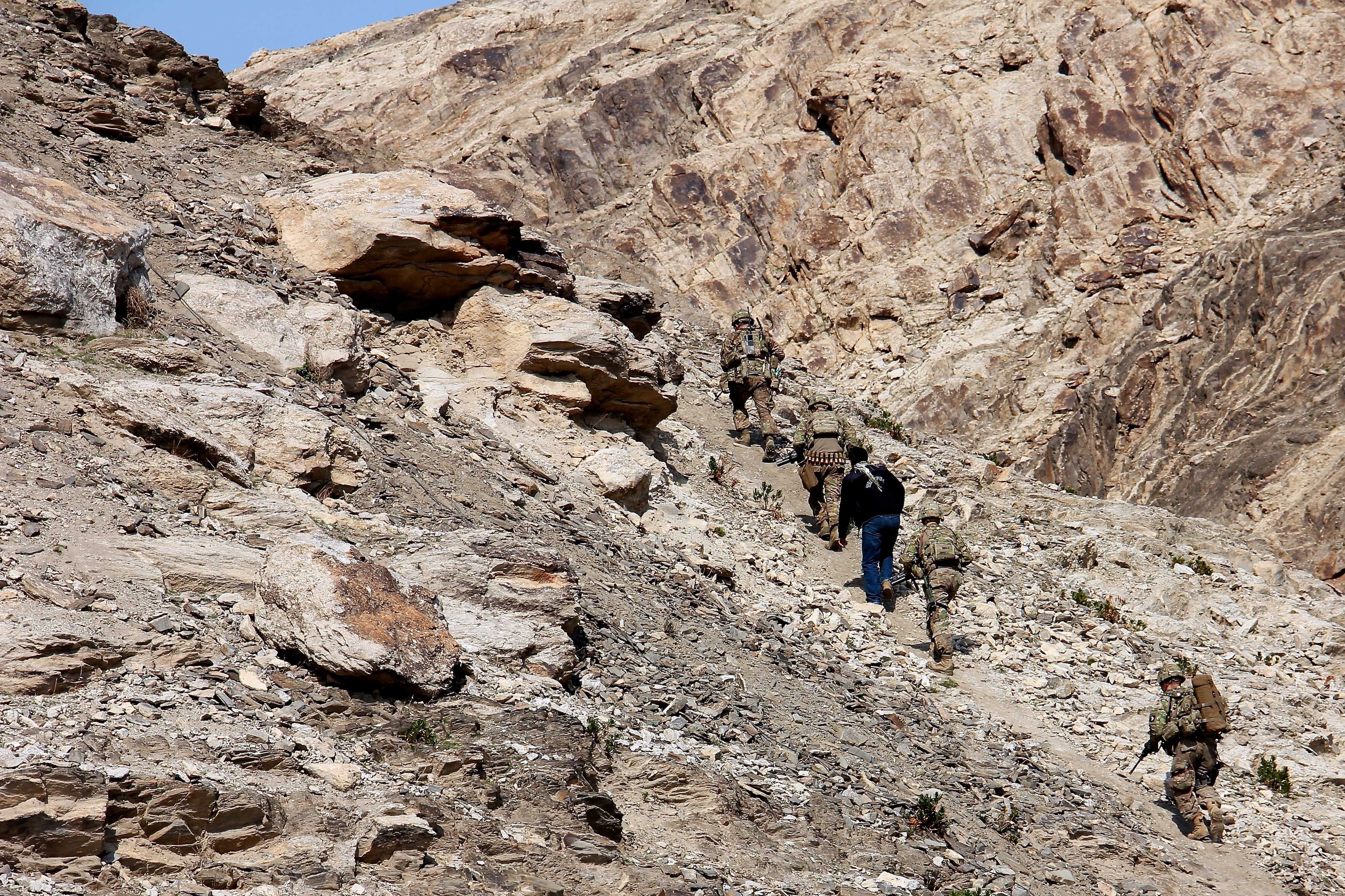 U.S. soldiers climb a mountain to an observation post to establish ...