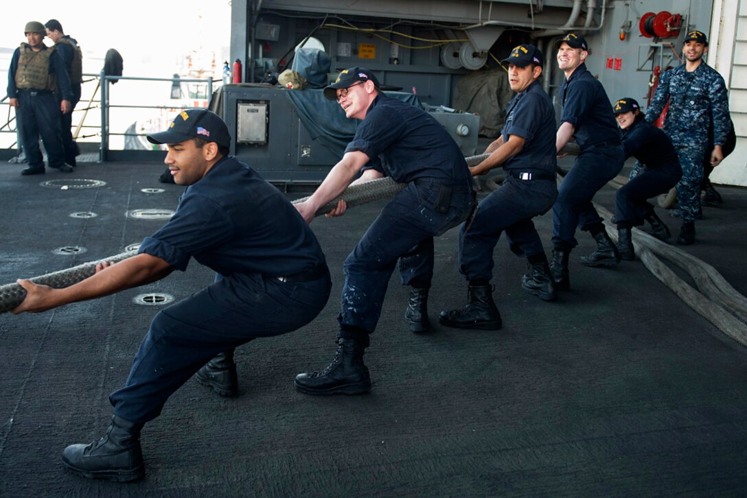 U.S. sailors heave a mooring line on the fantail of the aircraft ...
