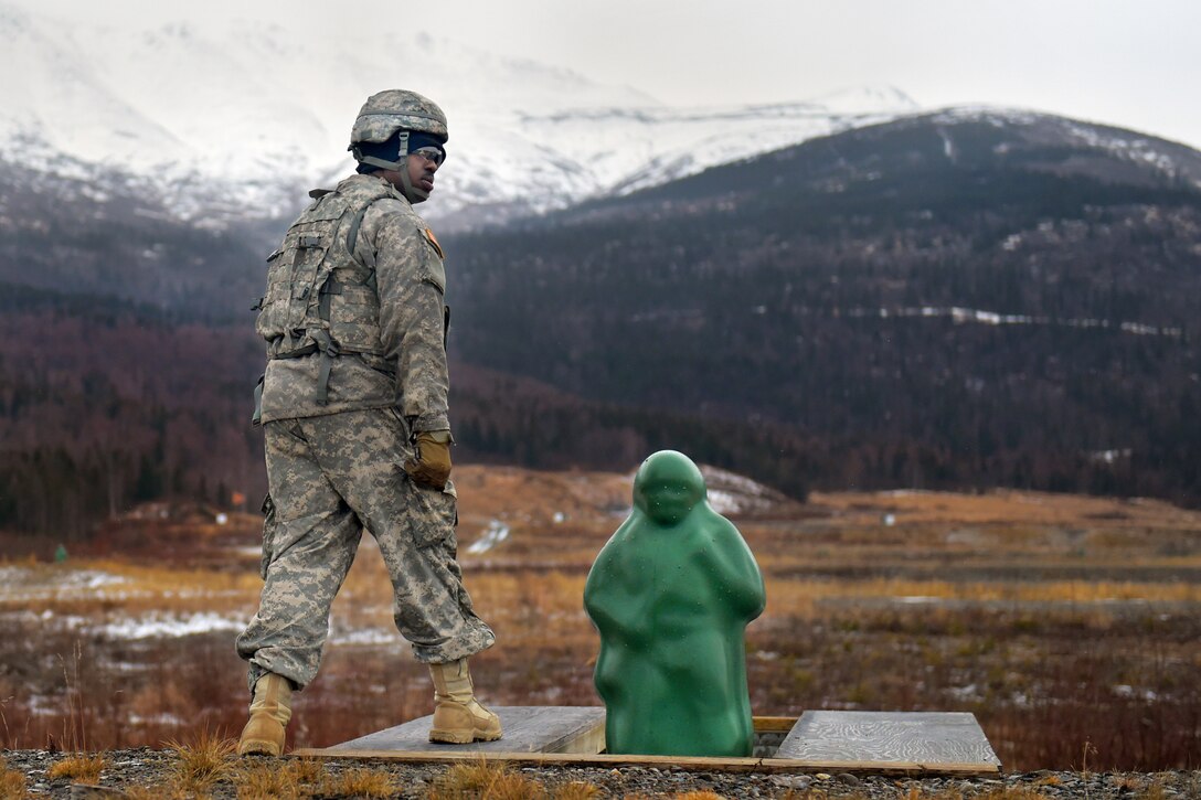 Army Pfc. James Travis stands next to a target after qualifying with ...