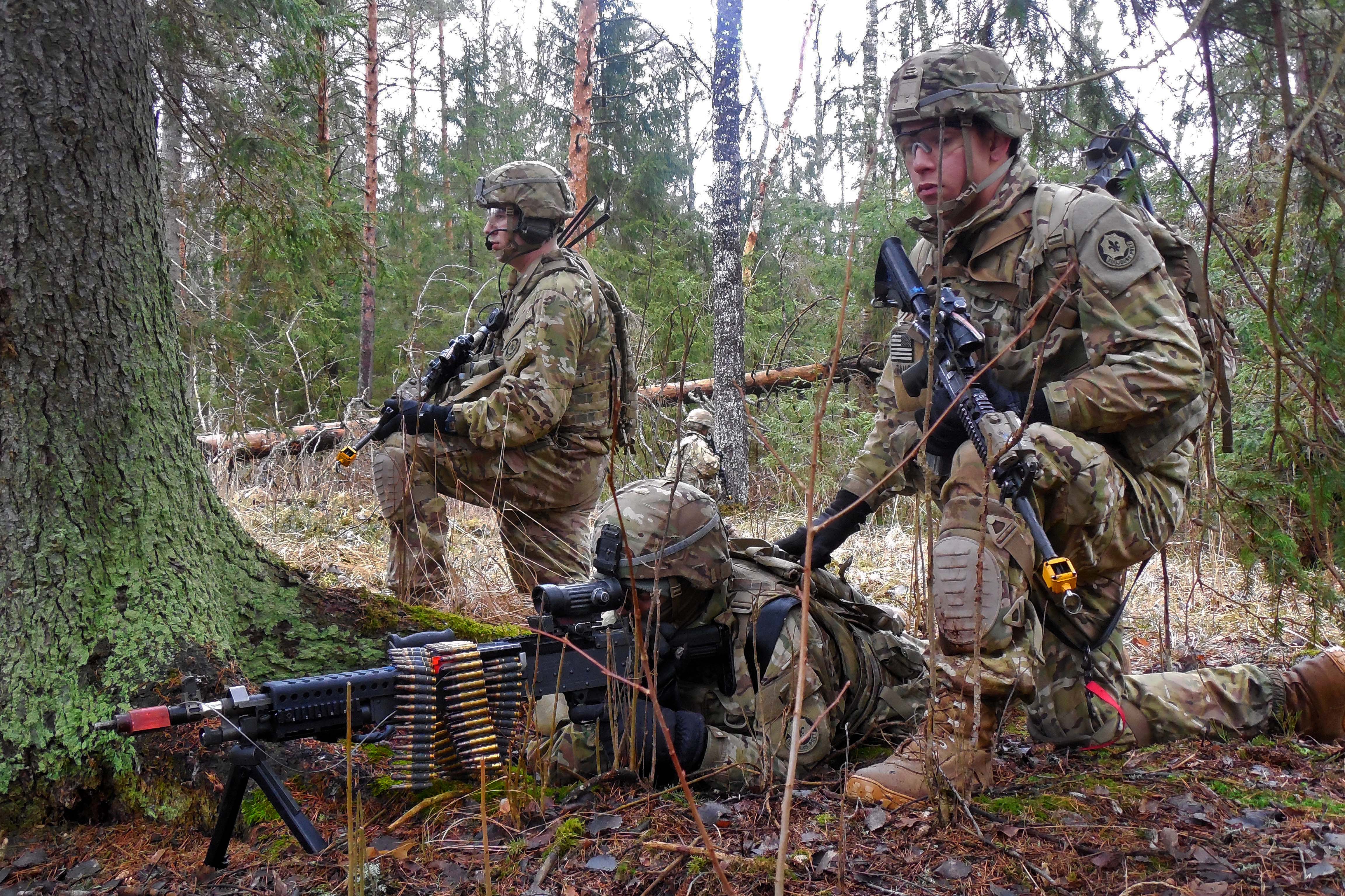 U.S. soldiers conduct a patrol halt while maneuvering through a forest ...
