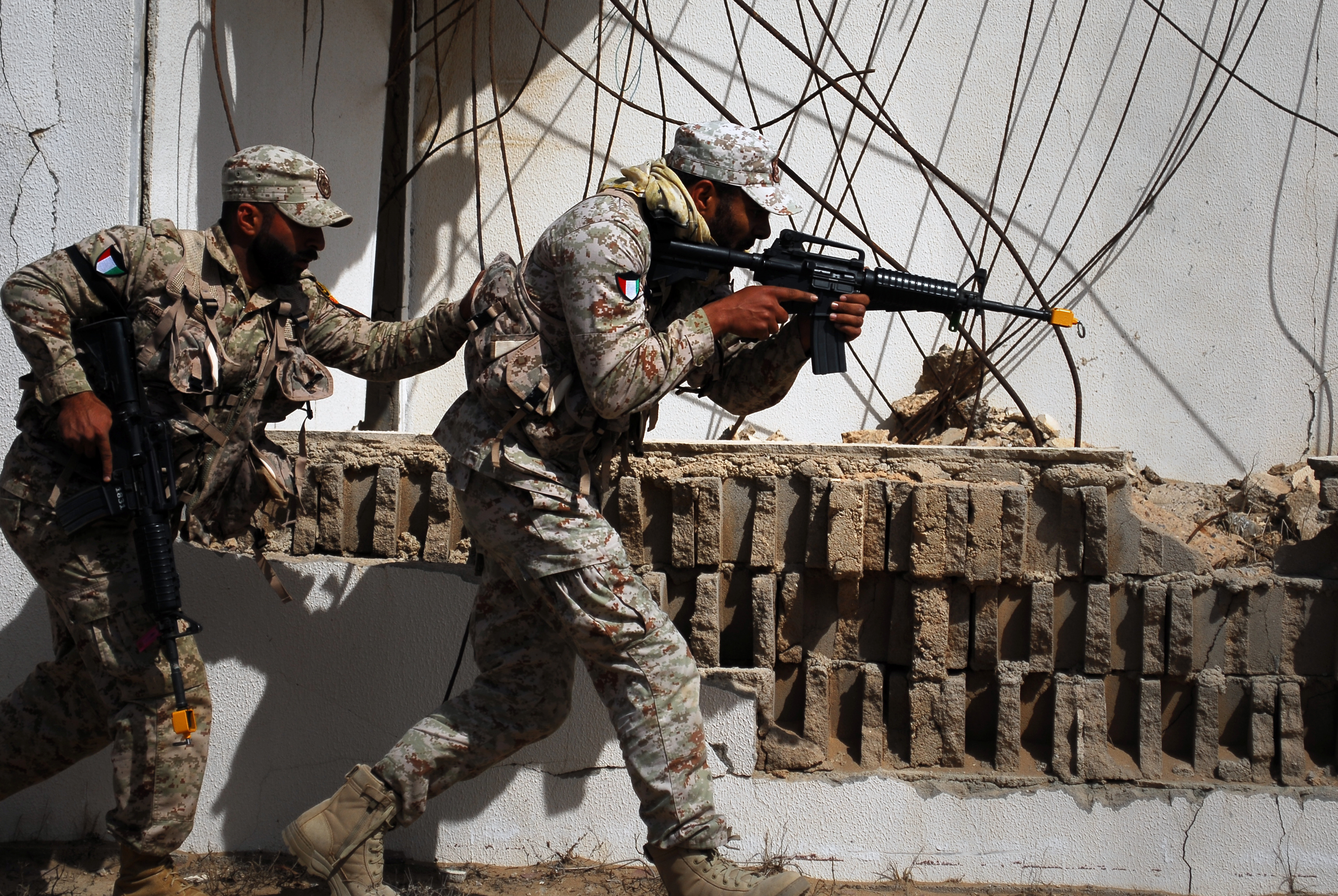 Two Kuwaiti soldiers move toward an objective during a simulated urban ...