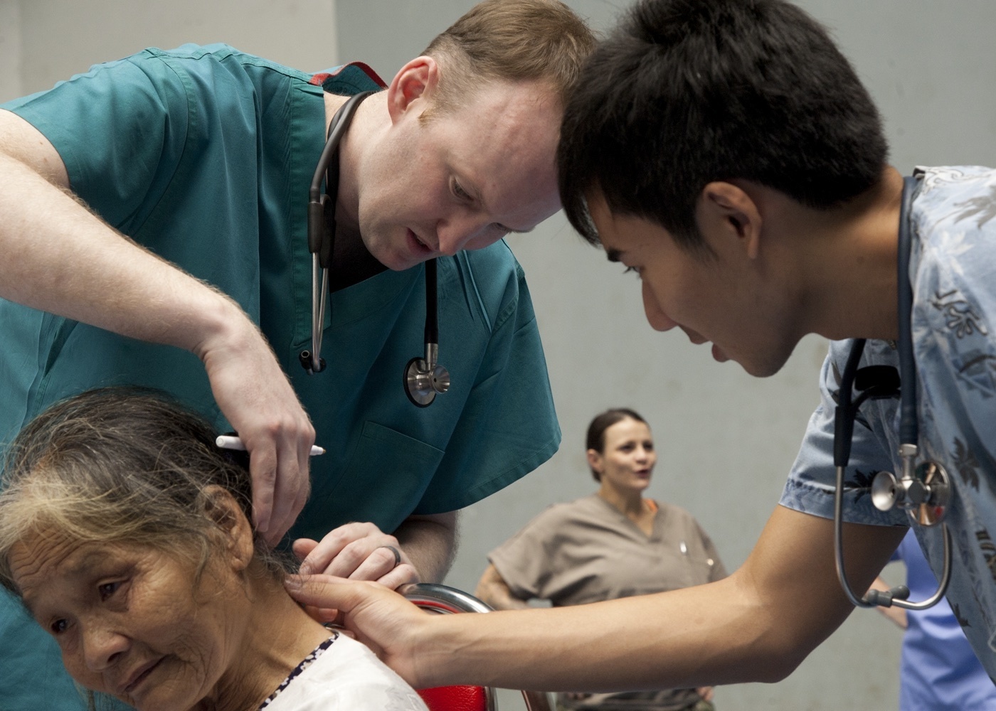 U.S. Air Force Capt. Aaron Goodrich examines a patient along with ...