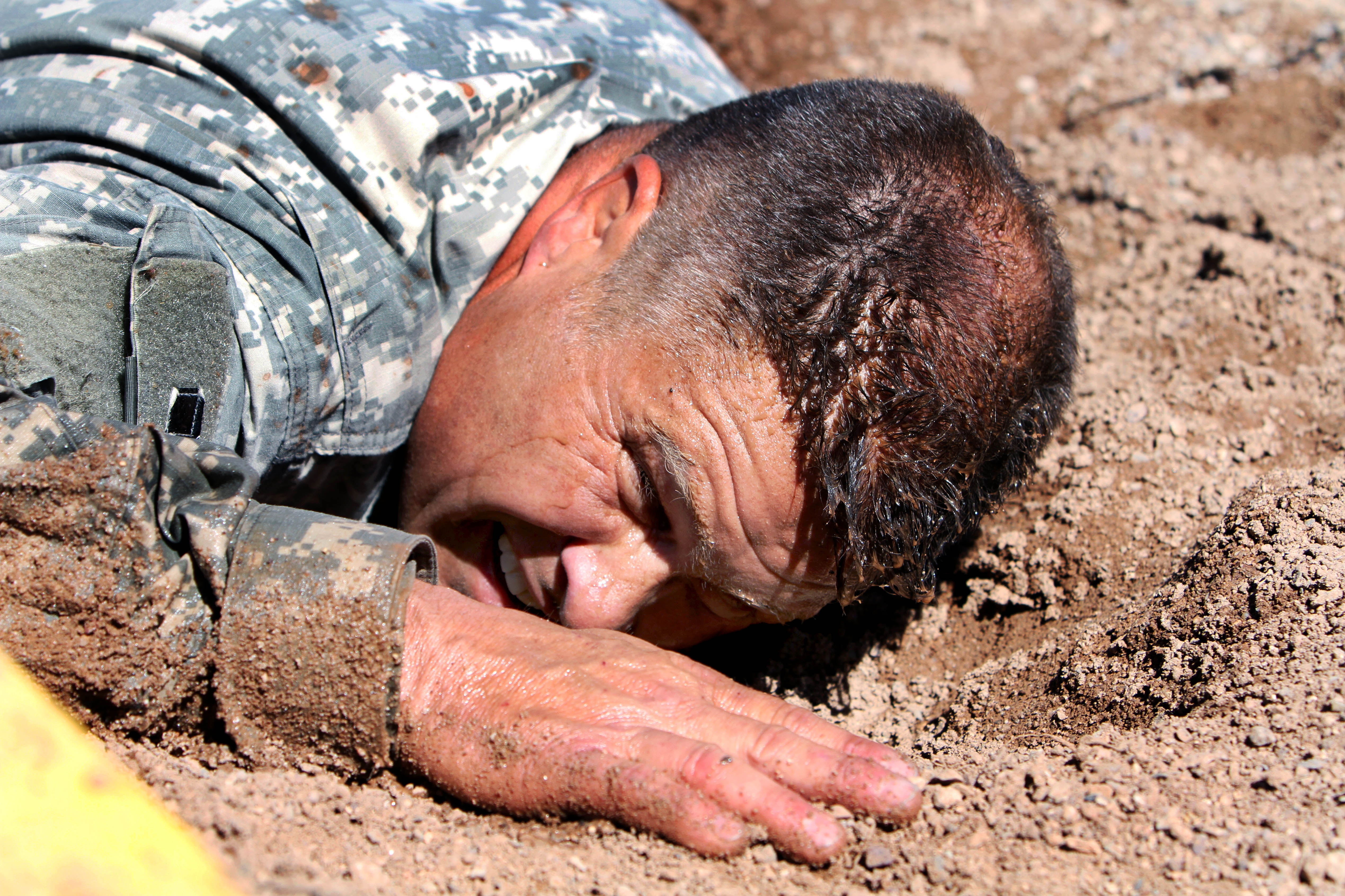 Army Staff Sgt. John Lueke pulls himself through the mud as he finishes ...