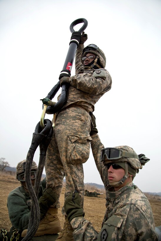 U.S. soldiers prepare to hook a howitzer system to a CH-47 Chinook ...