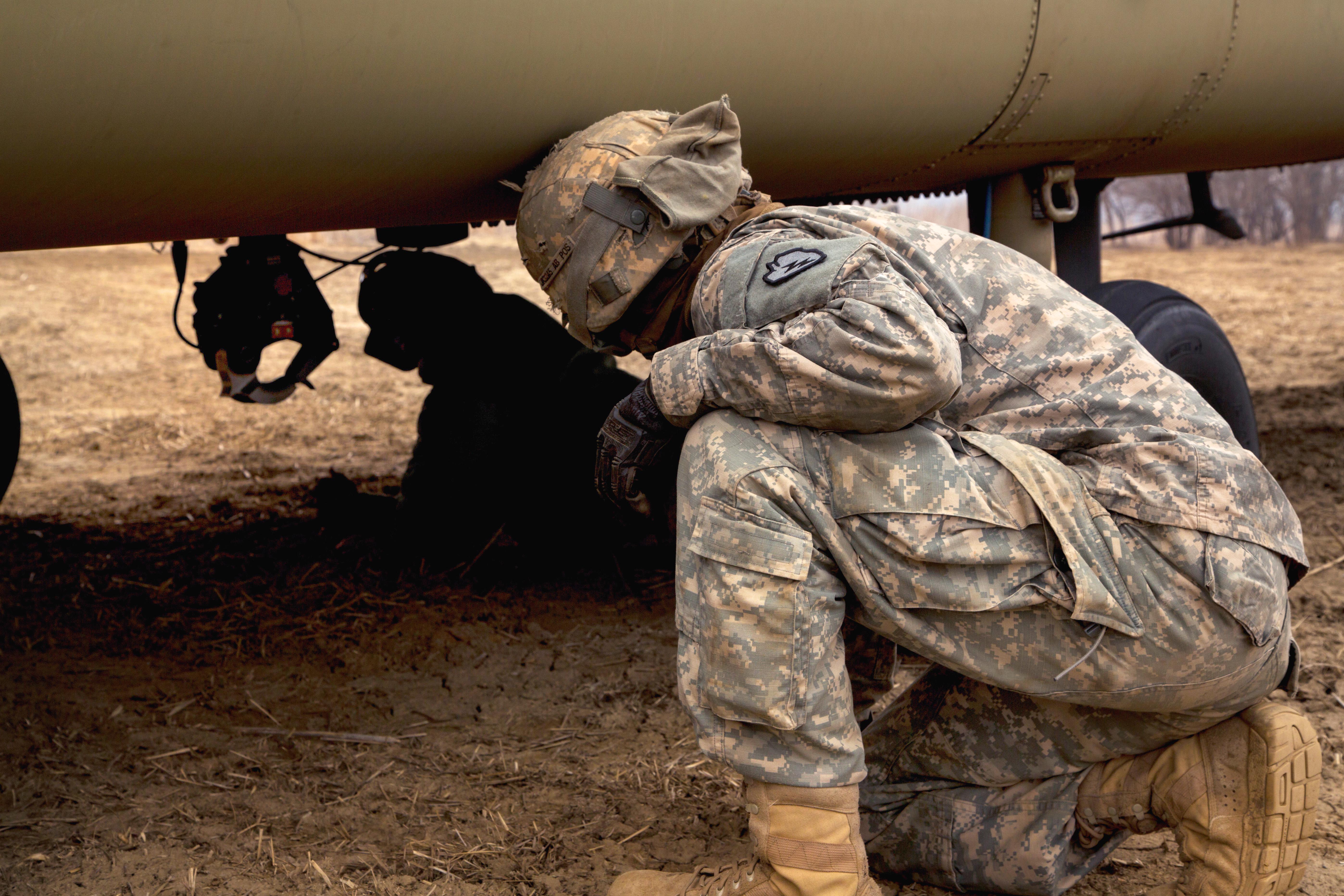 U.S. soldiers inspect the cargo hook under a CH-47 Chinook helicopter ...