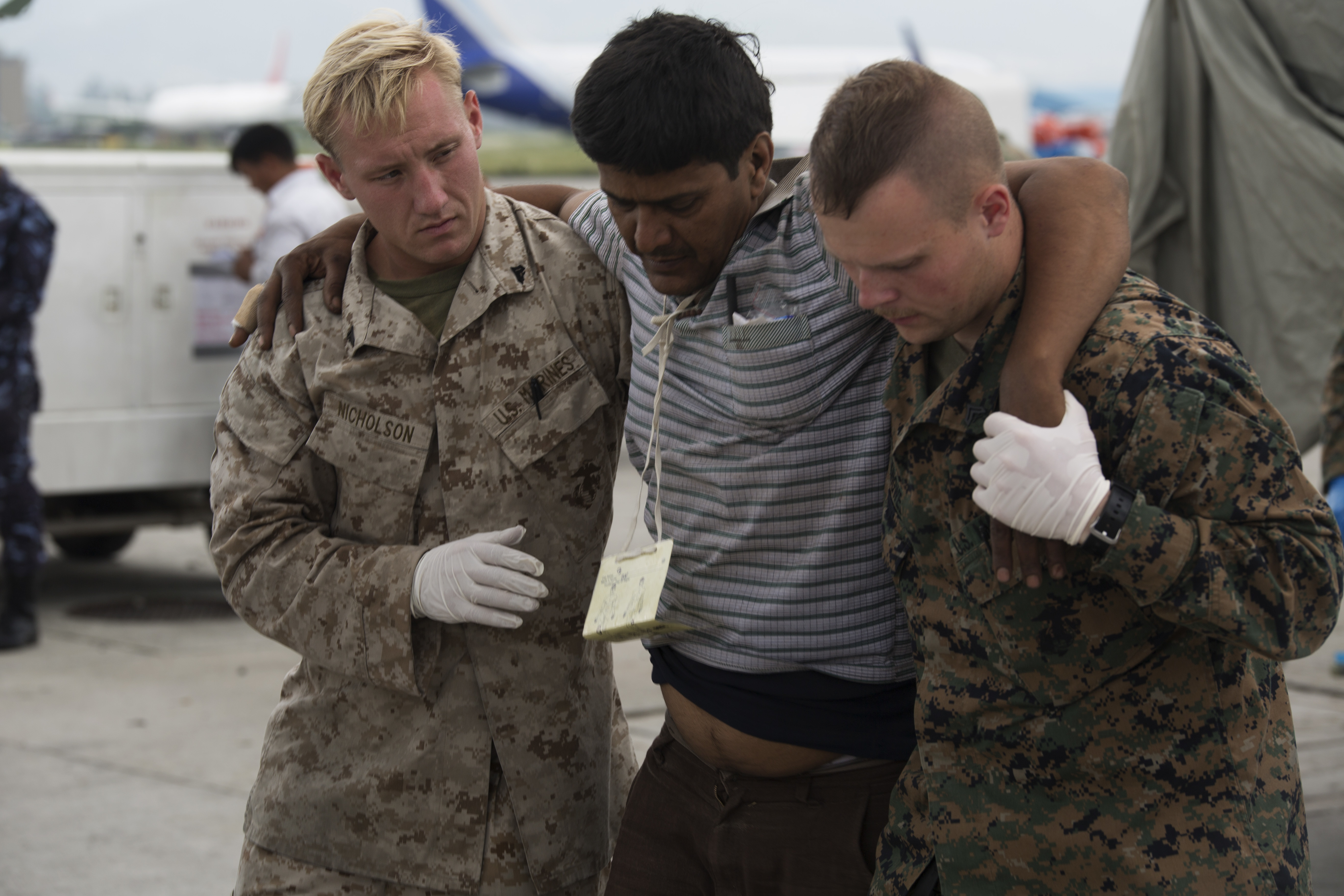 U.S. Marines help a Nepalese man to a triage at the Tribhuvan ...