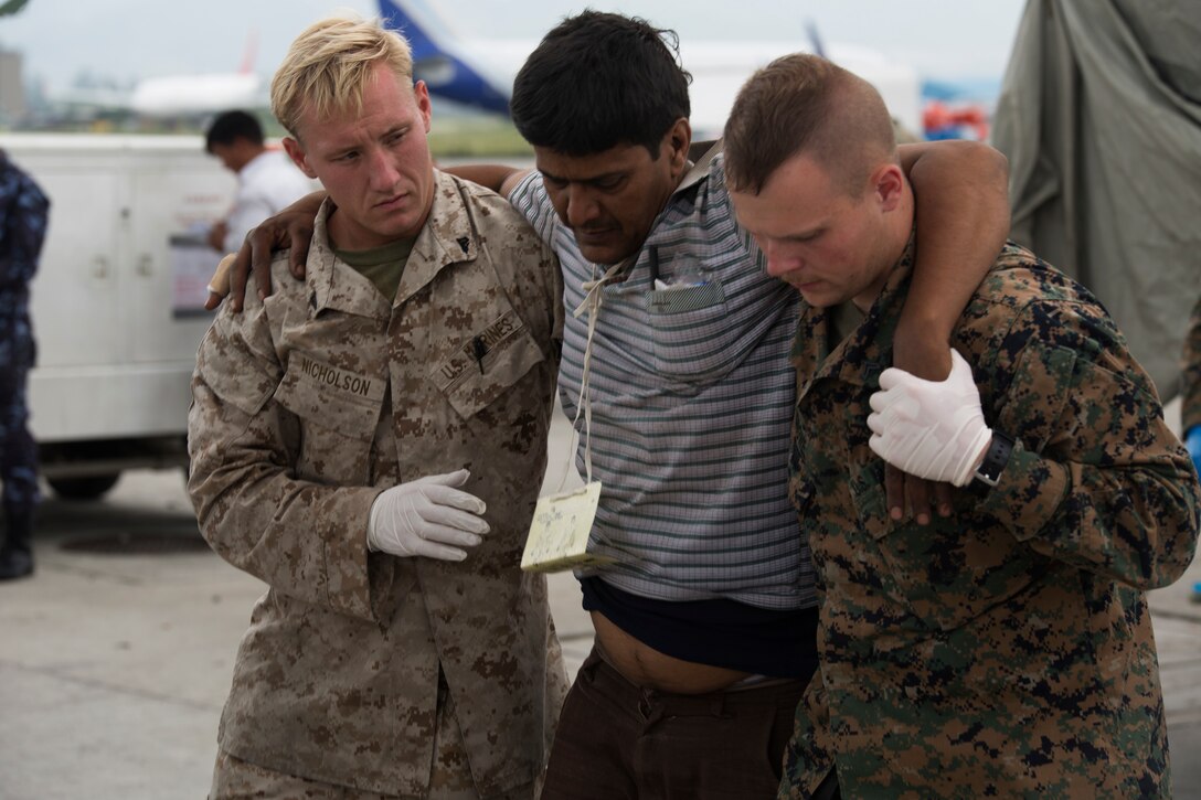 U.S. Marines help a Nepalese man to a triage at the Tribhuvan ...