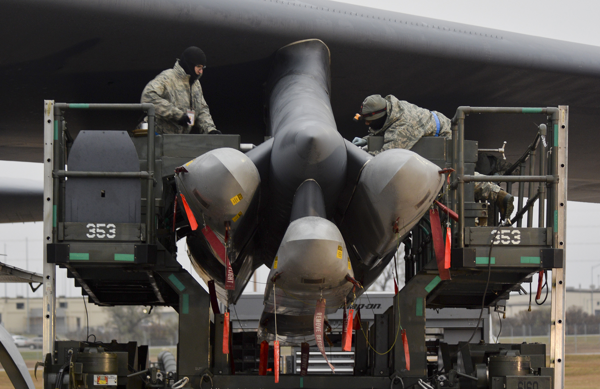 Cruise missiles are loaded under the wing of a B-52 Stratofortress ...