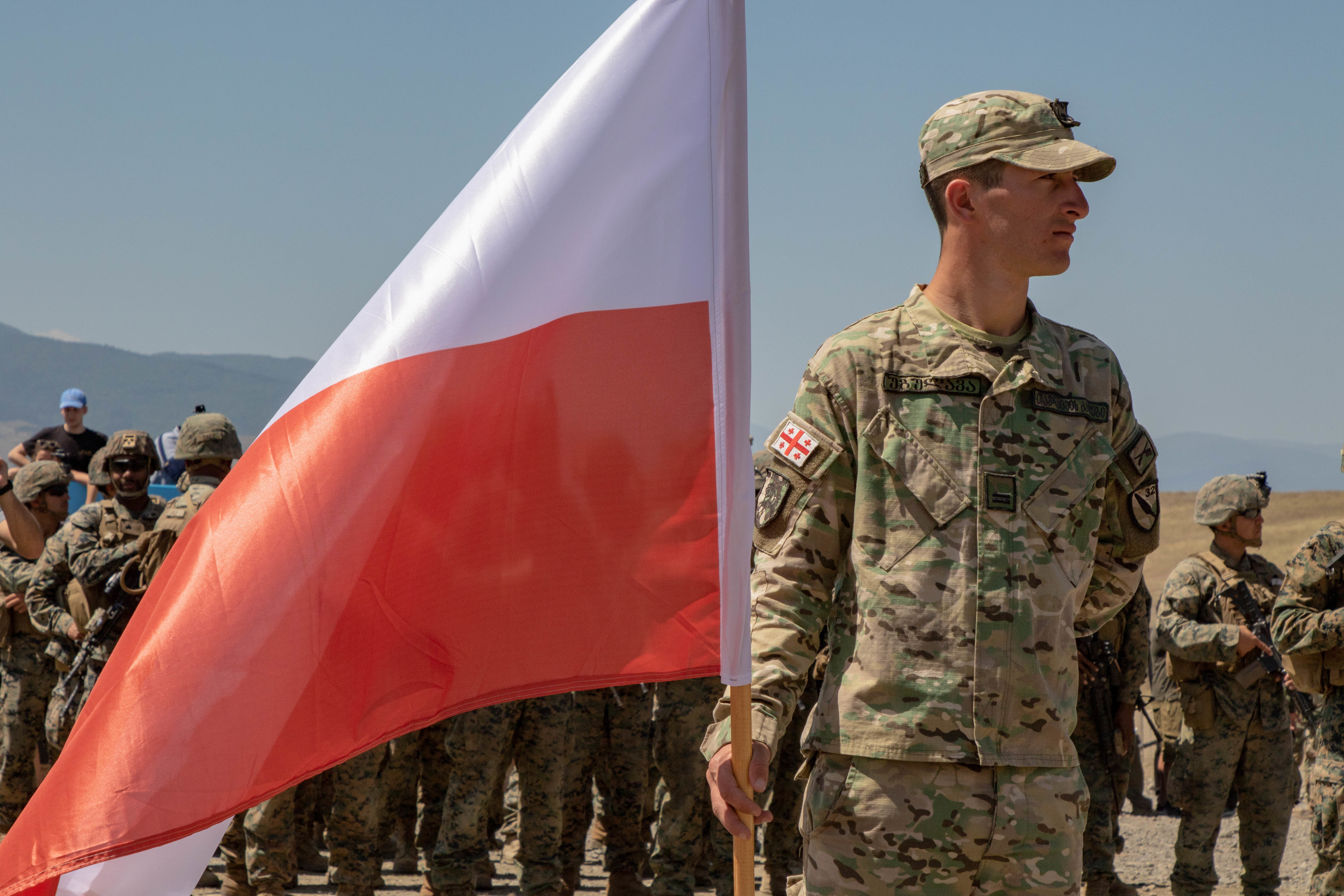 A Georgian Defense Force soldier holds the flag of Poland