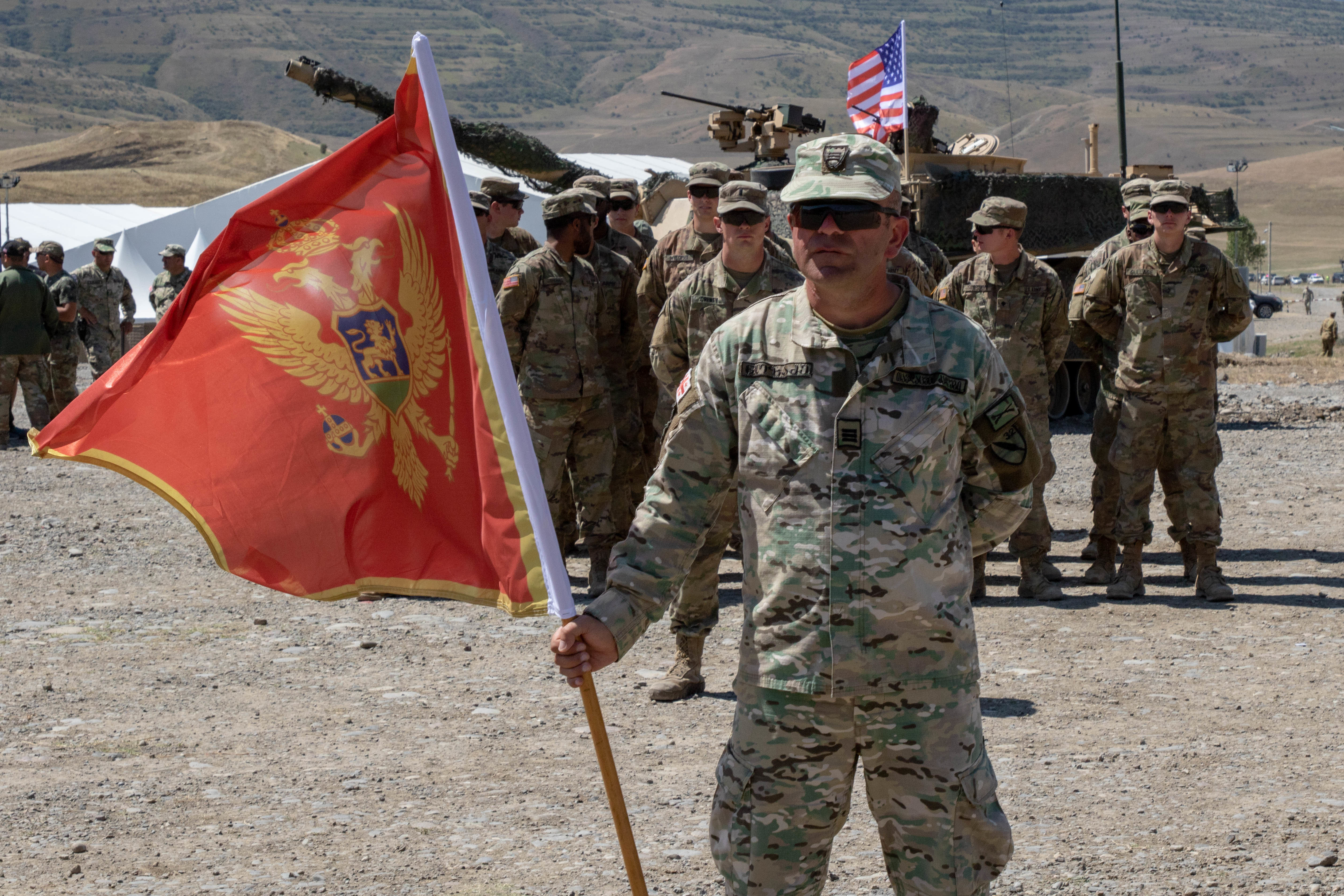 A Georgian Defense Force soldier holds the flag of Montenegro