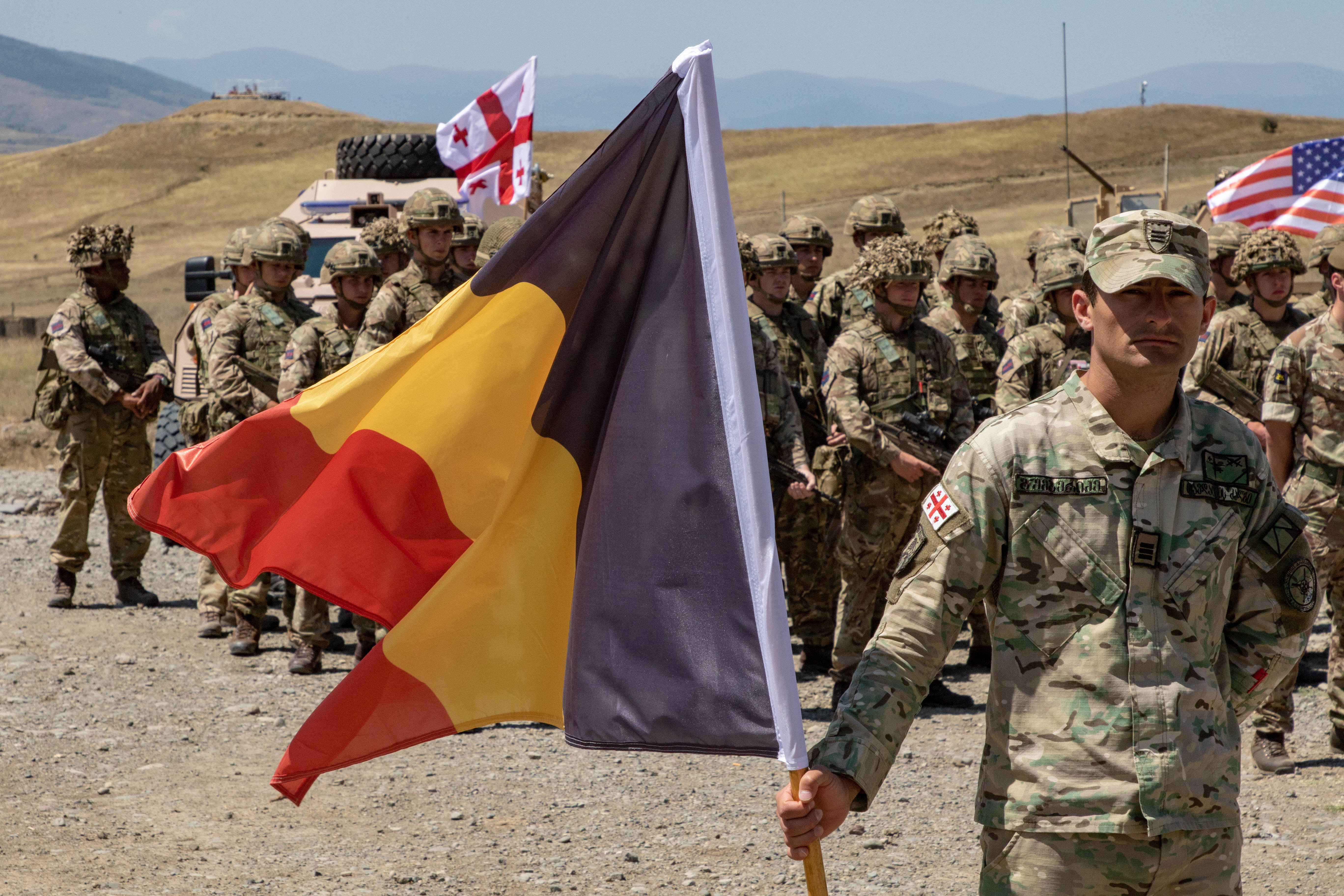 A Georgian Defense Force soldier holds the flag of Belgium