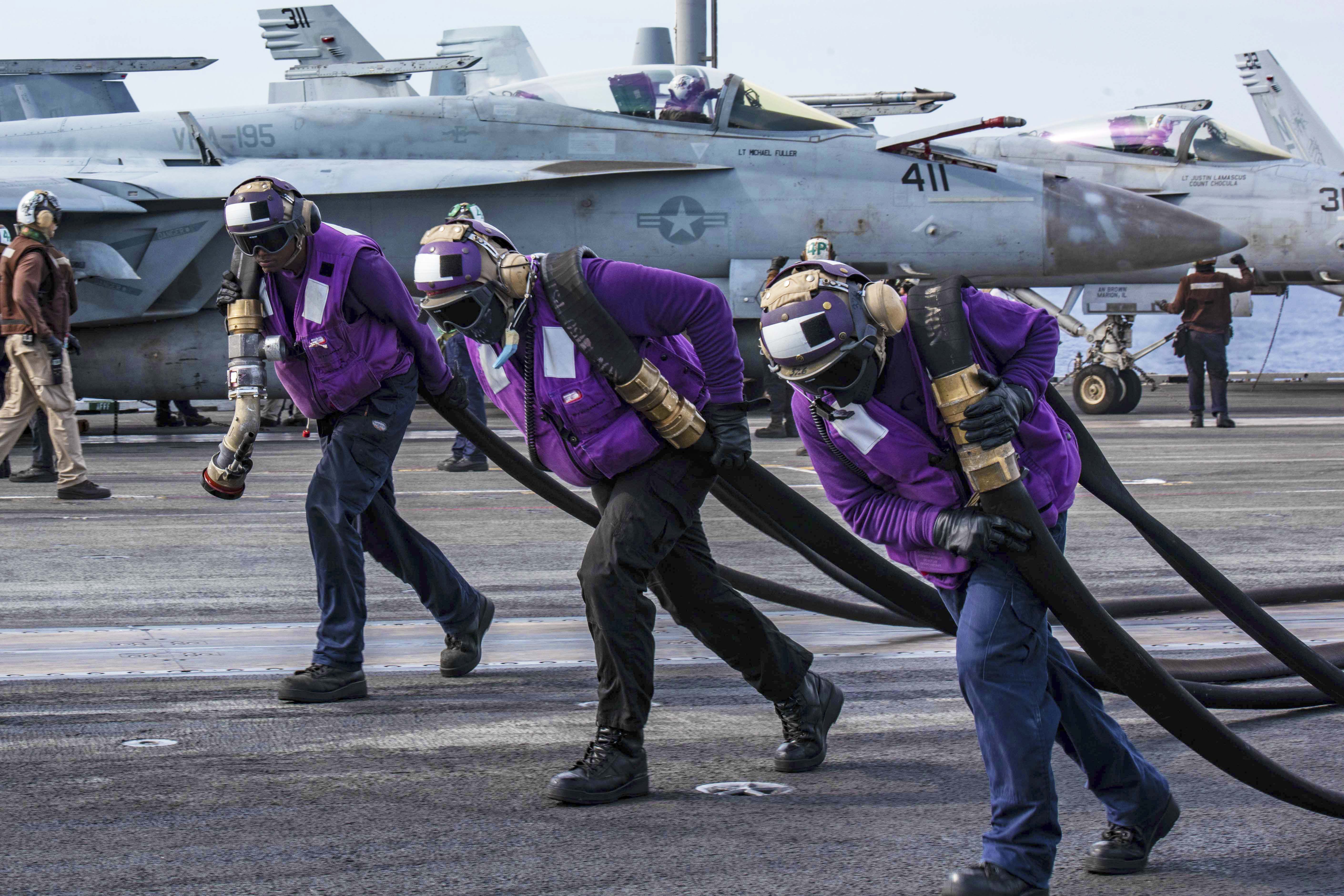 Sailors move fuel hoses on the flight deck of the USS Ronald Reagan ...