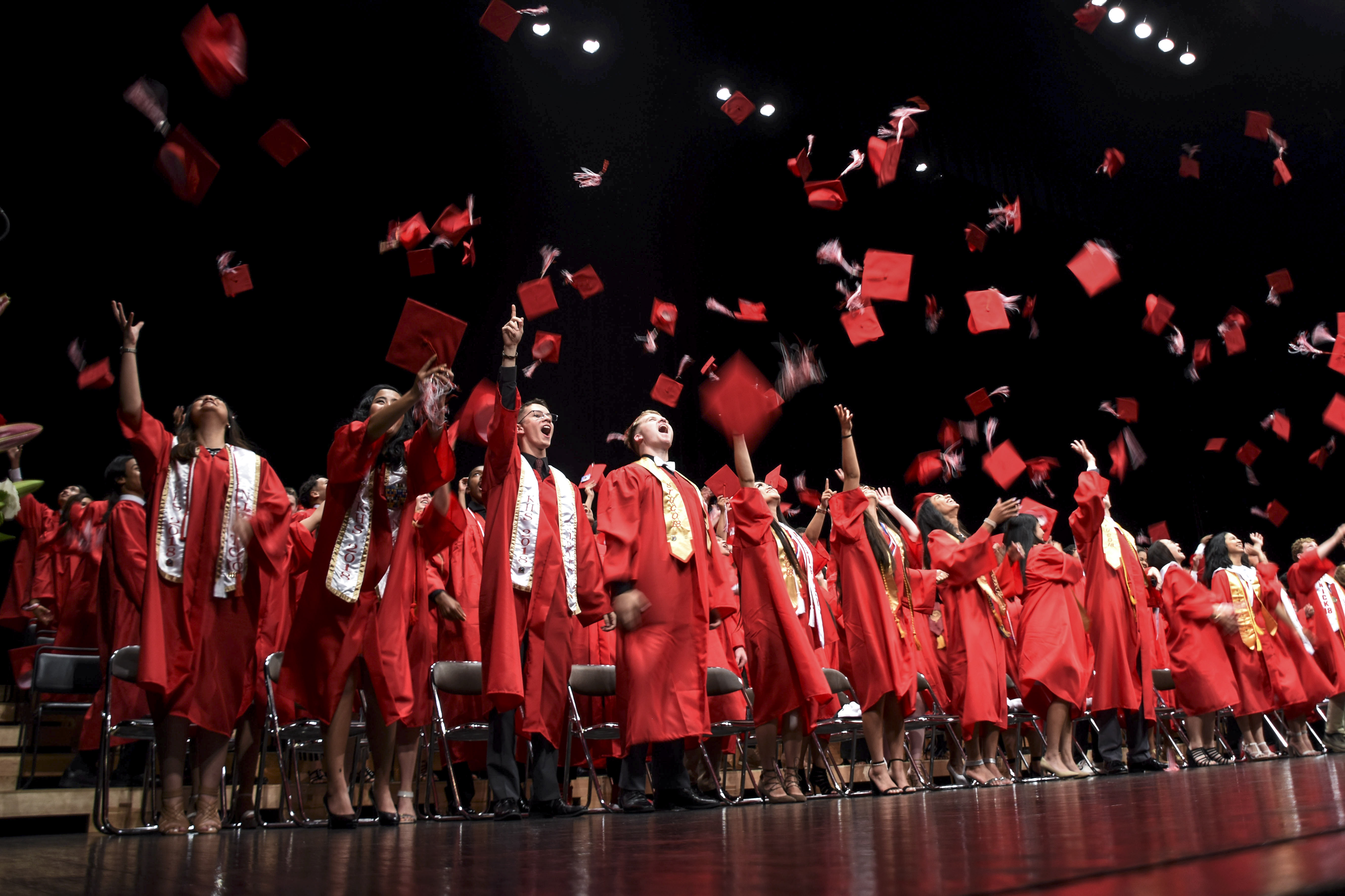 Red Graduation Caps In The Air