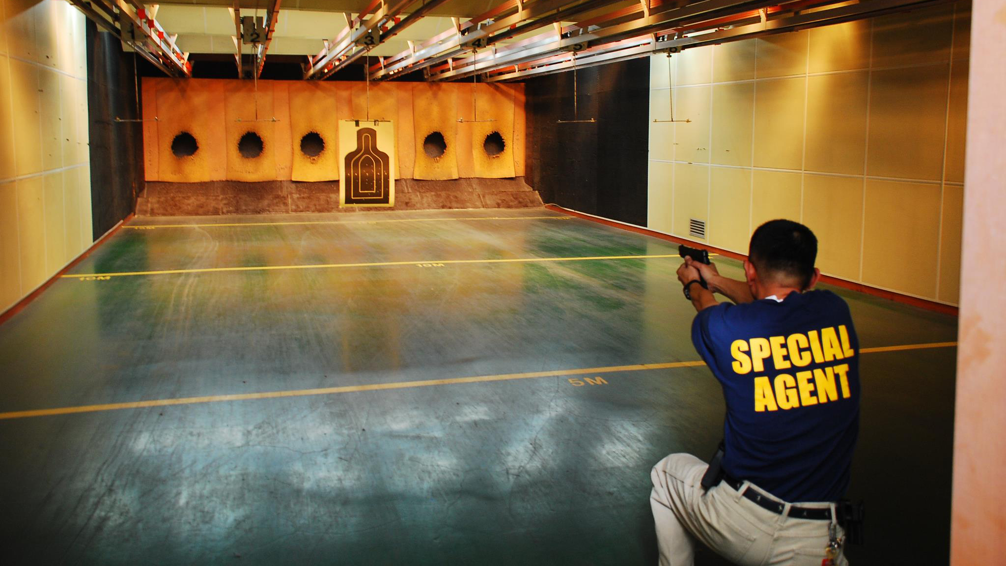 CID agent at indoor range engaging targets with sidearm