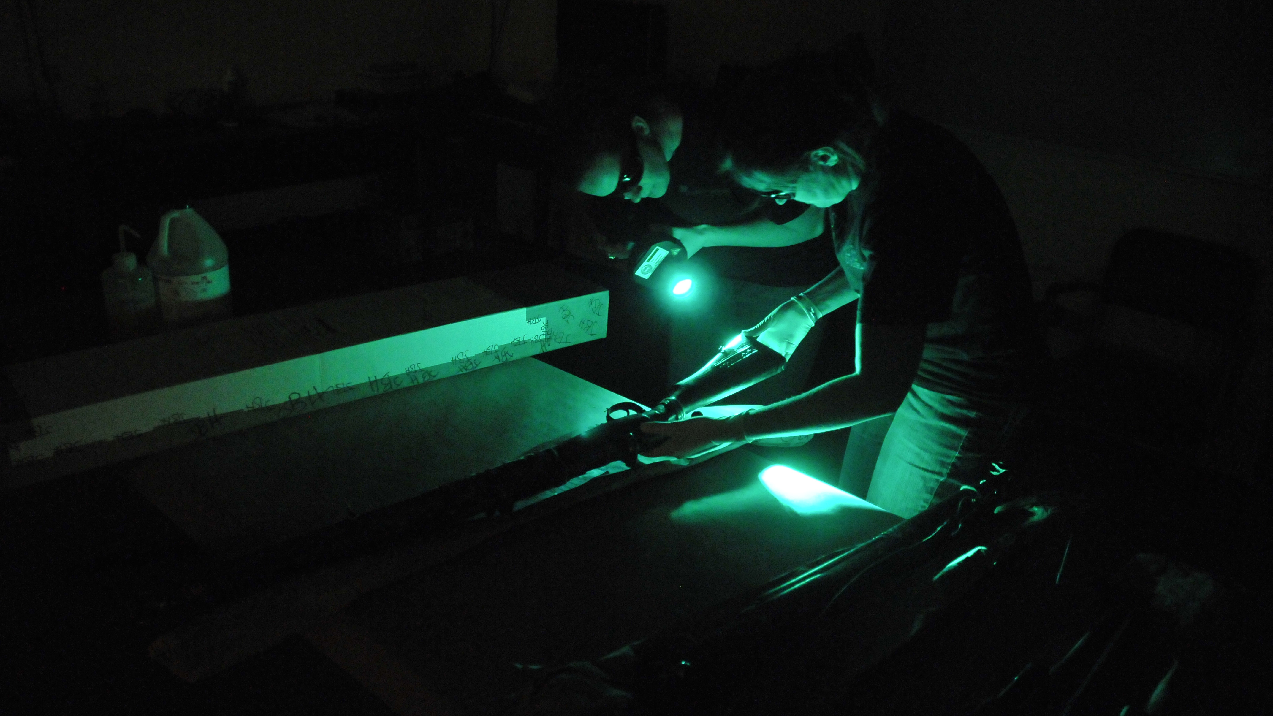 Army CID agent uses a special lighting system to examine evidence in ...